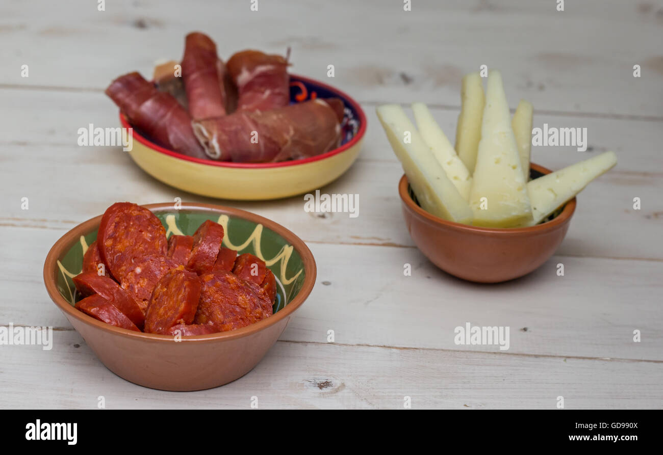 Tapas, chorizo, manchego, and cured ham on a wooden table Stock Photo ...