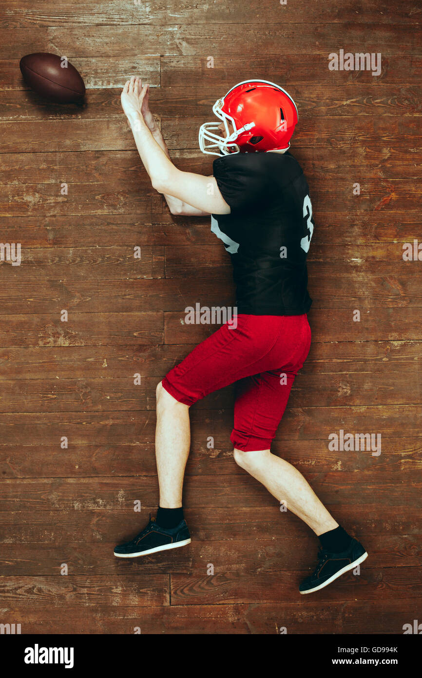 Top view photo of handsome young american football player on wooden ...