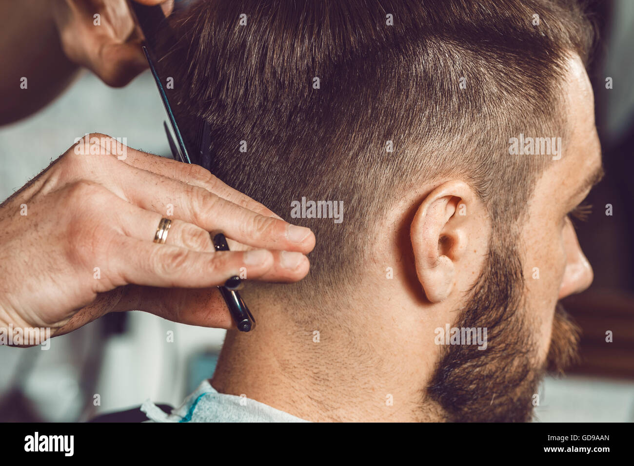 The hands of young barber making haircut to attractive man in ...