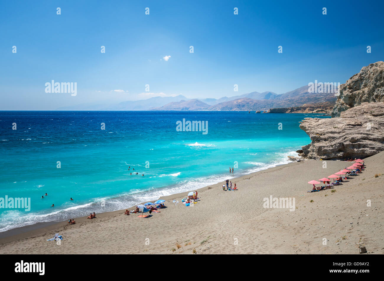 Agios Pavlos Beach in Crete island, Greece. Tourists relax and bath in crystal clear water of St ...