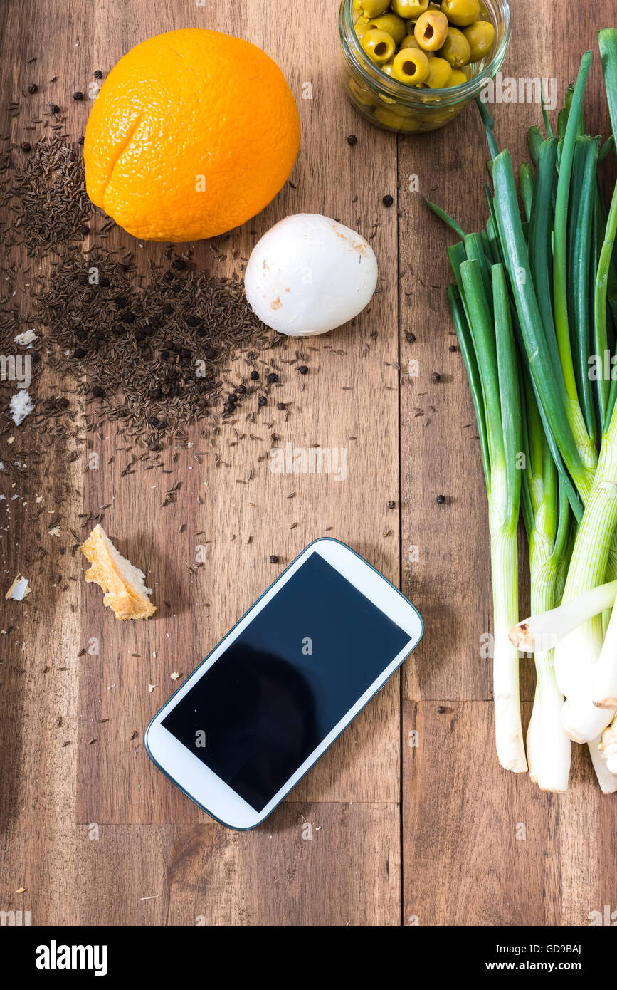 A smartphone lying in a natural kitchen with white bread, spices ...