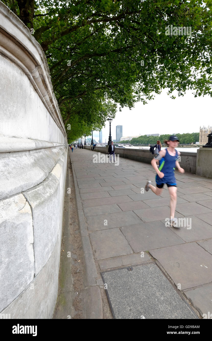 A jogger runs along the South Bank of the river Thames City of London ...