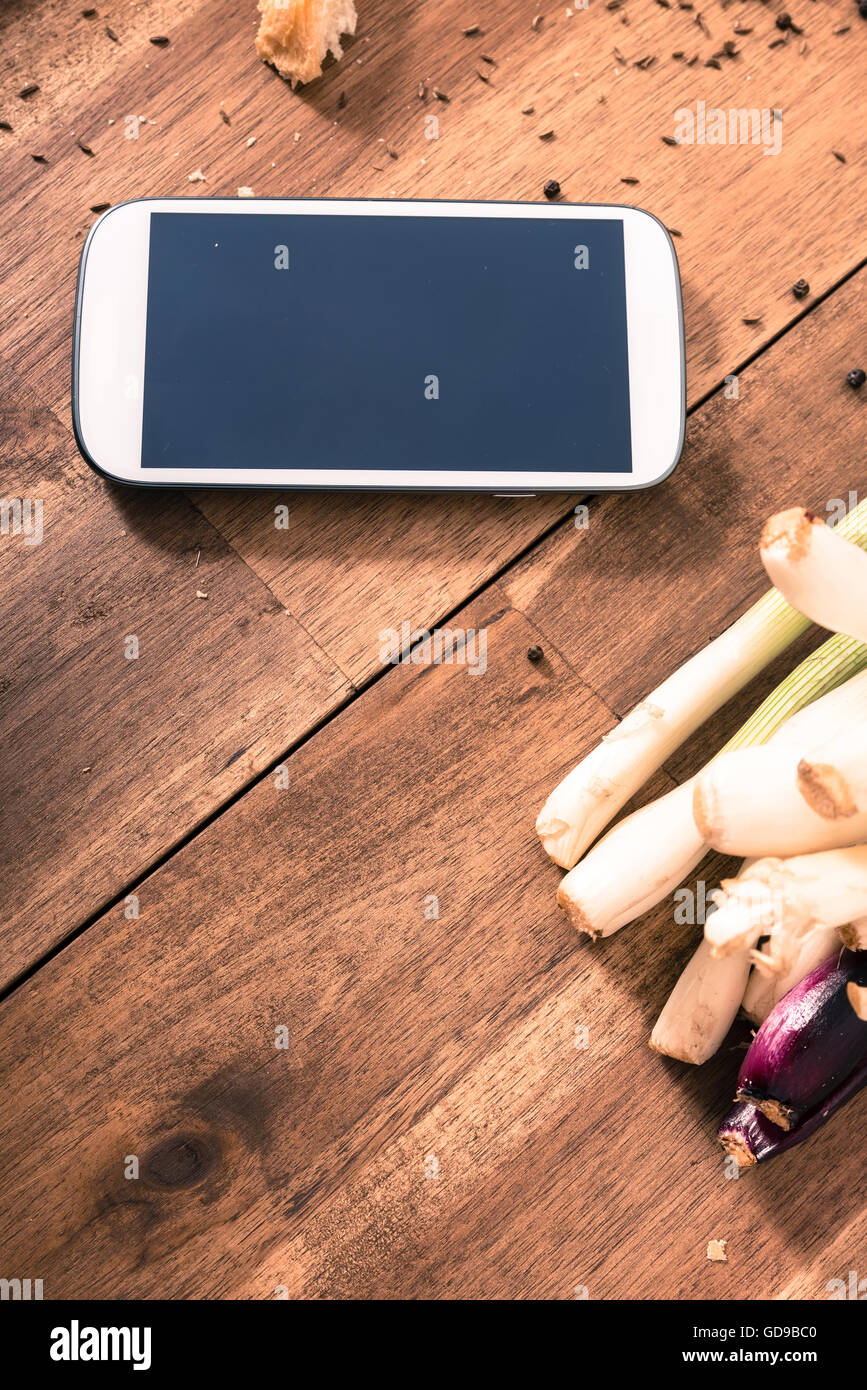 A smartphone lying in a natural kitchen with white bread, spices ...