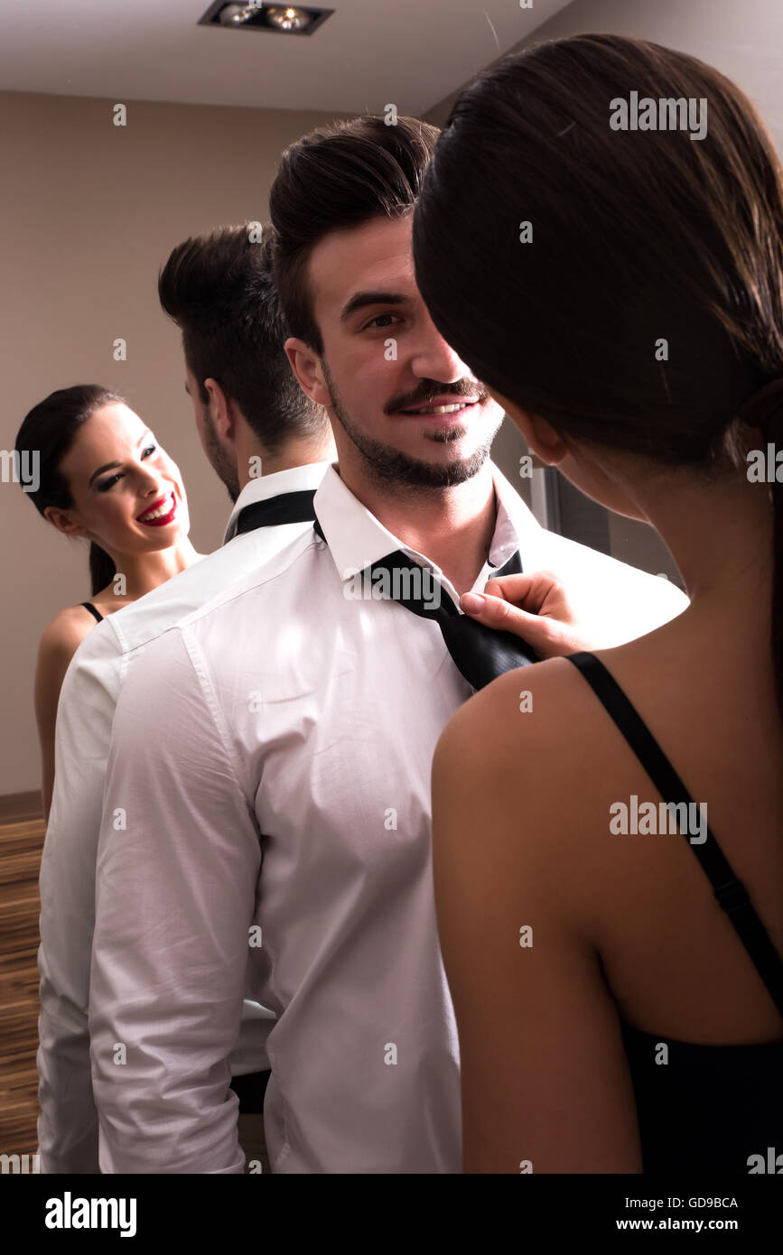 A young couple preparing to go out and getting ready and dressed in the ...