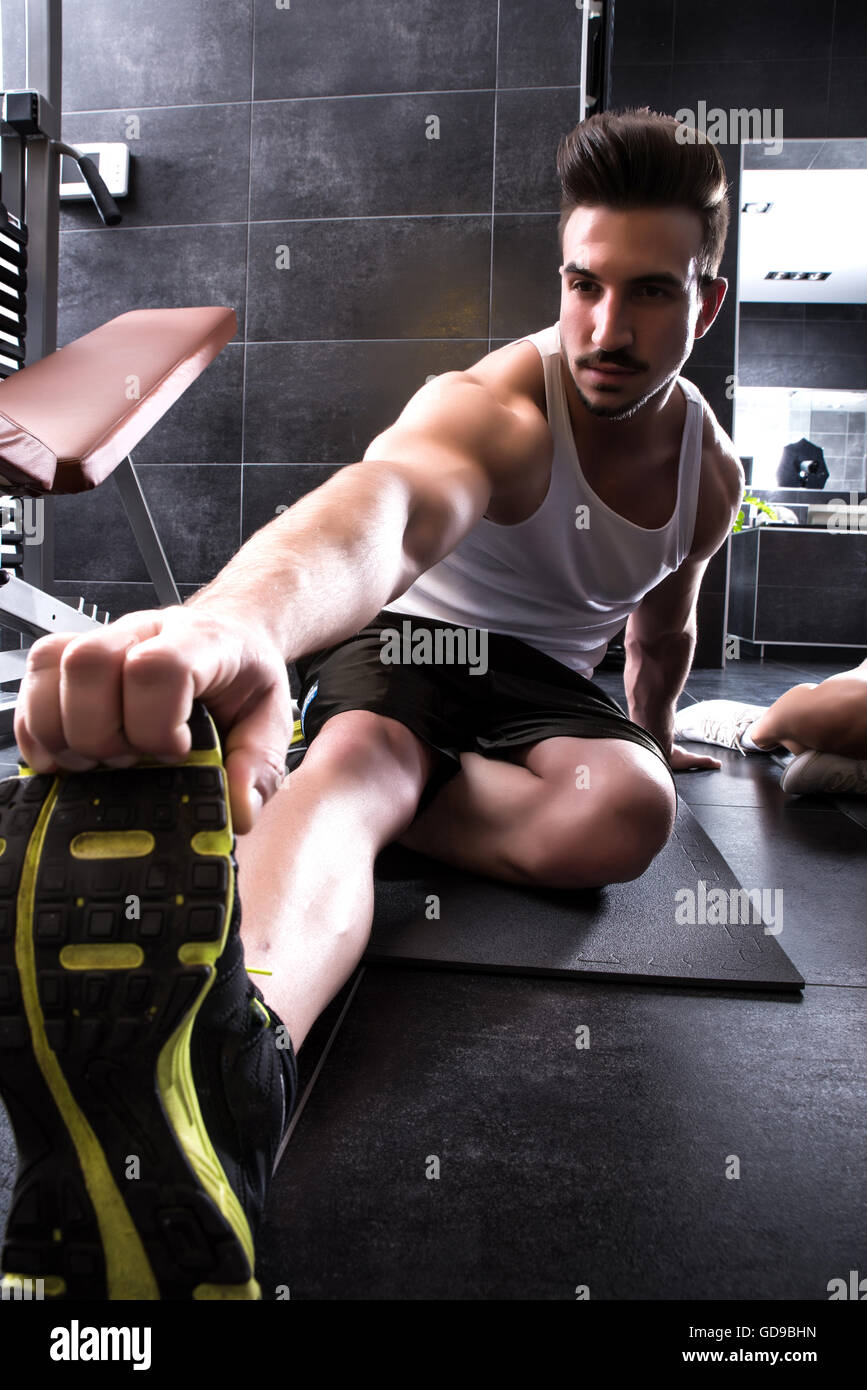 Young, handsome man stretching in the gym Stock Photo - Alamy