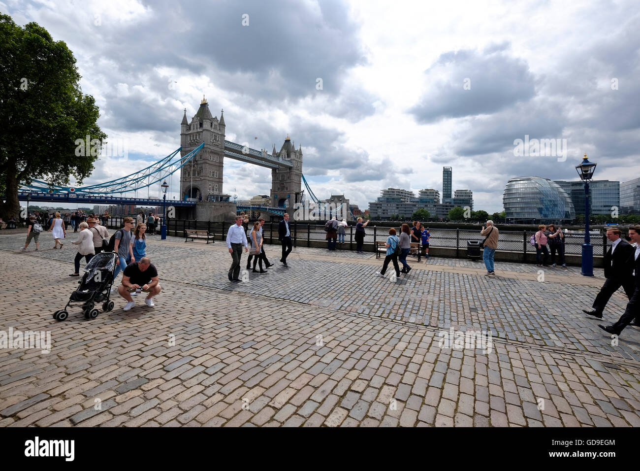 Tourists on Victoria Embankment London with Tower Bridge on the left ...