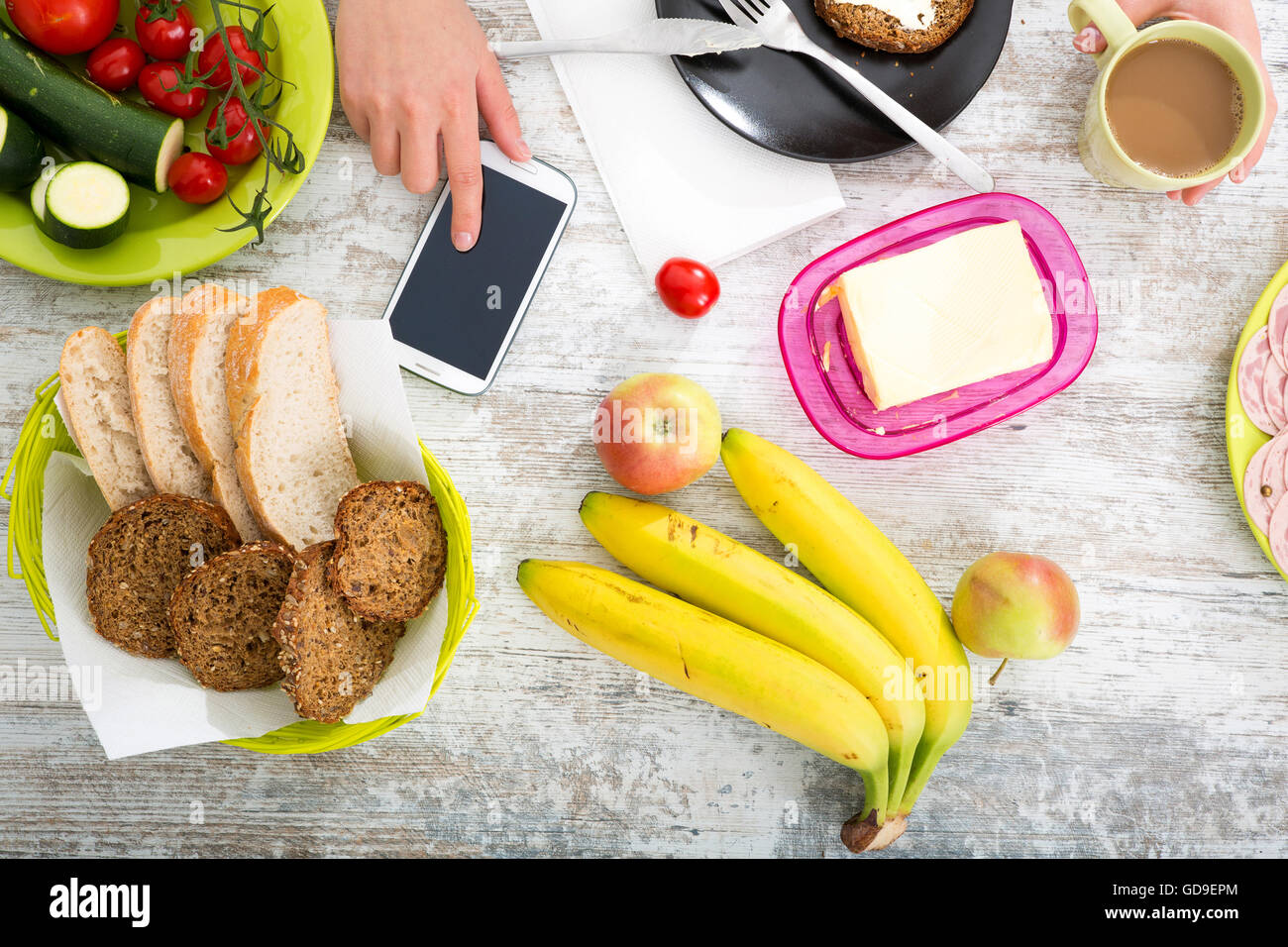 A woman having a breakfast at a table, while using a phone Stock Photo ...