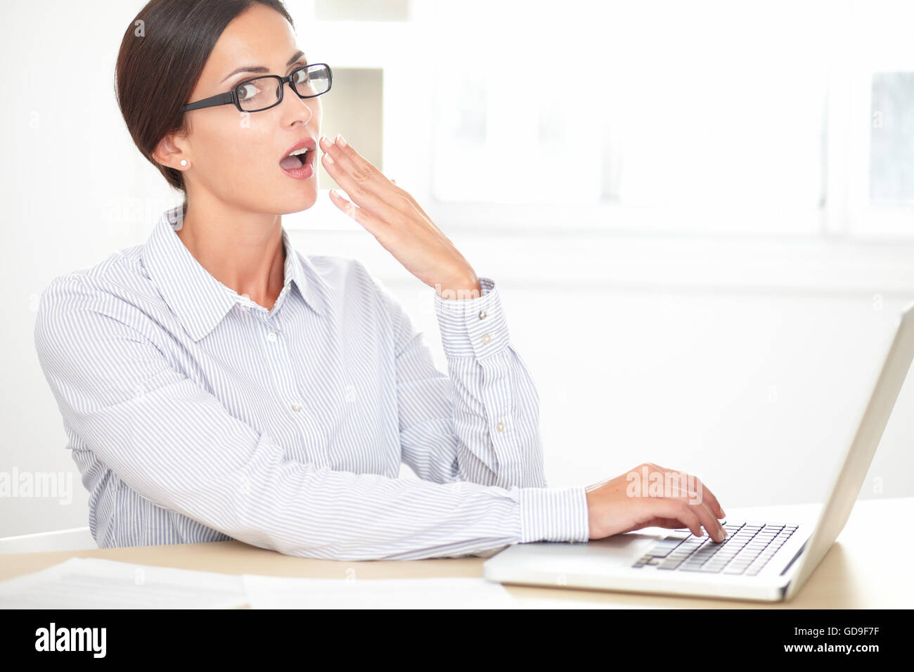 Business employee with glasses looking shocked while working on her ...