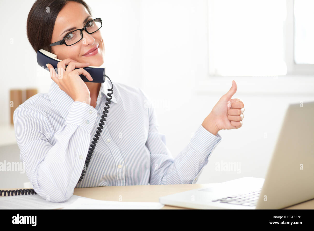 Latin employee with spectacles happily doing customer service in the ...