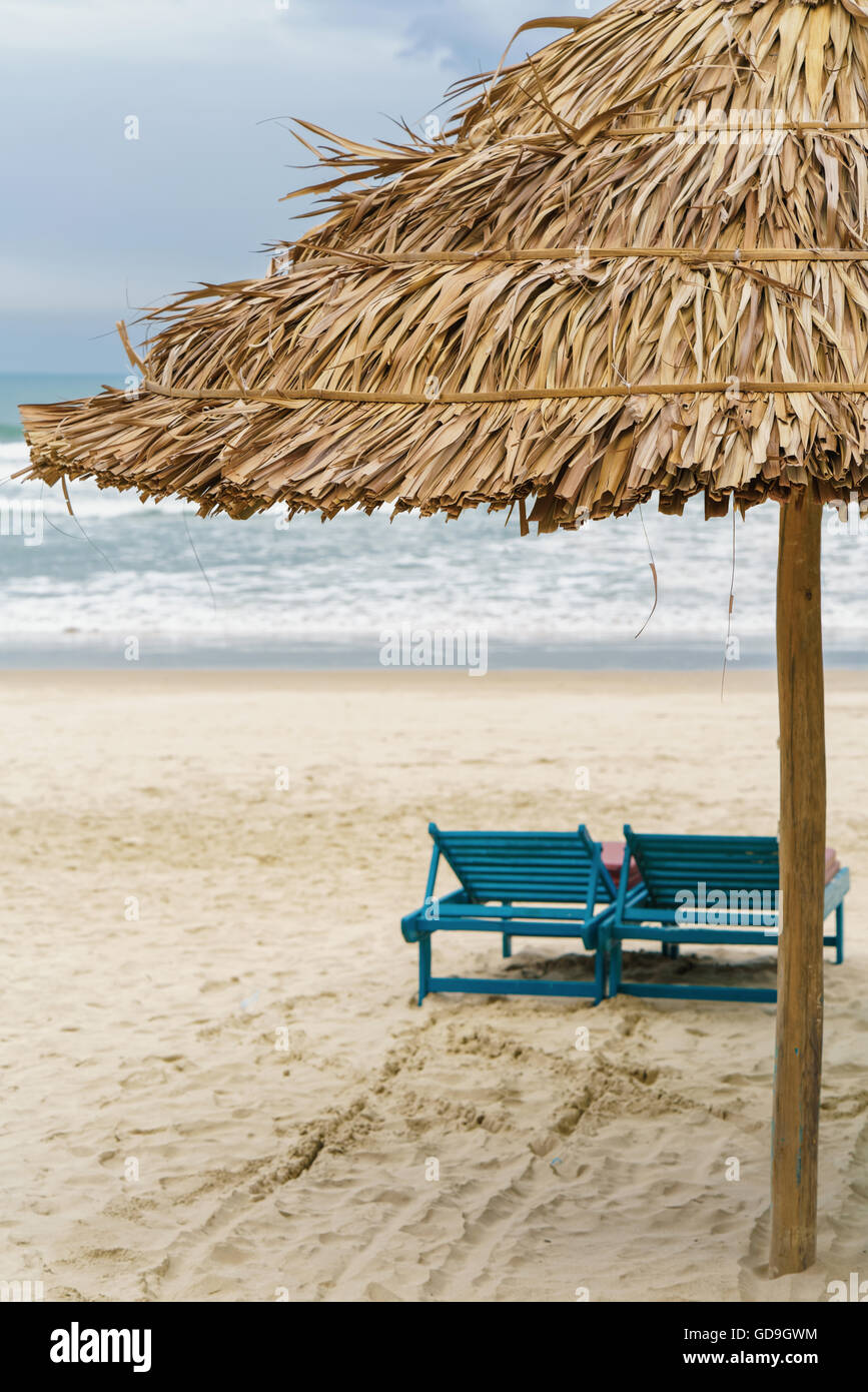 Palm shelter and sunbeds in the China Beach in Da Nang, Vietnam. It is ...
