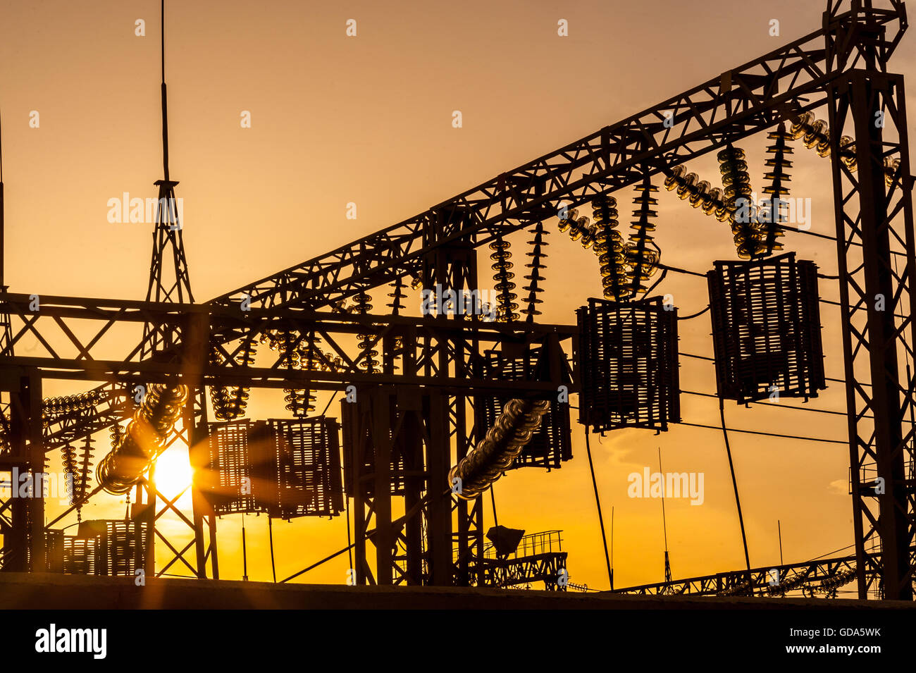 Electric lines, poles and glass isolators in a power station at sunset ...
