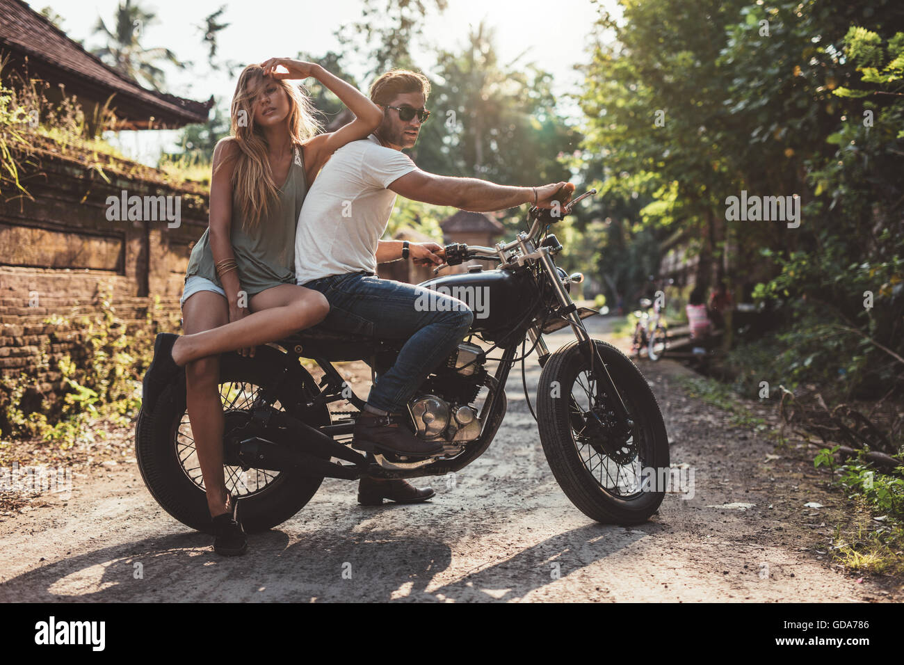 Portrait of young couple hanging out in countryside with motorcycle ...