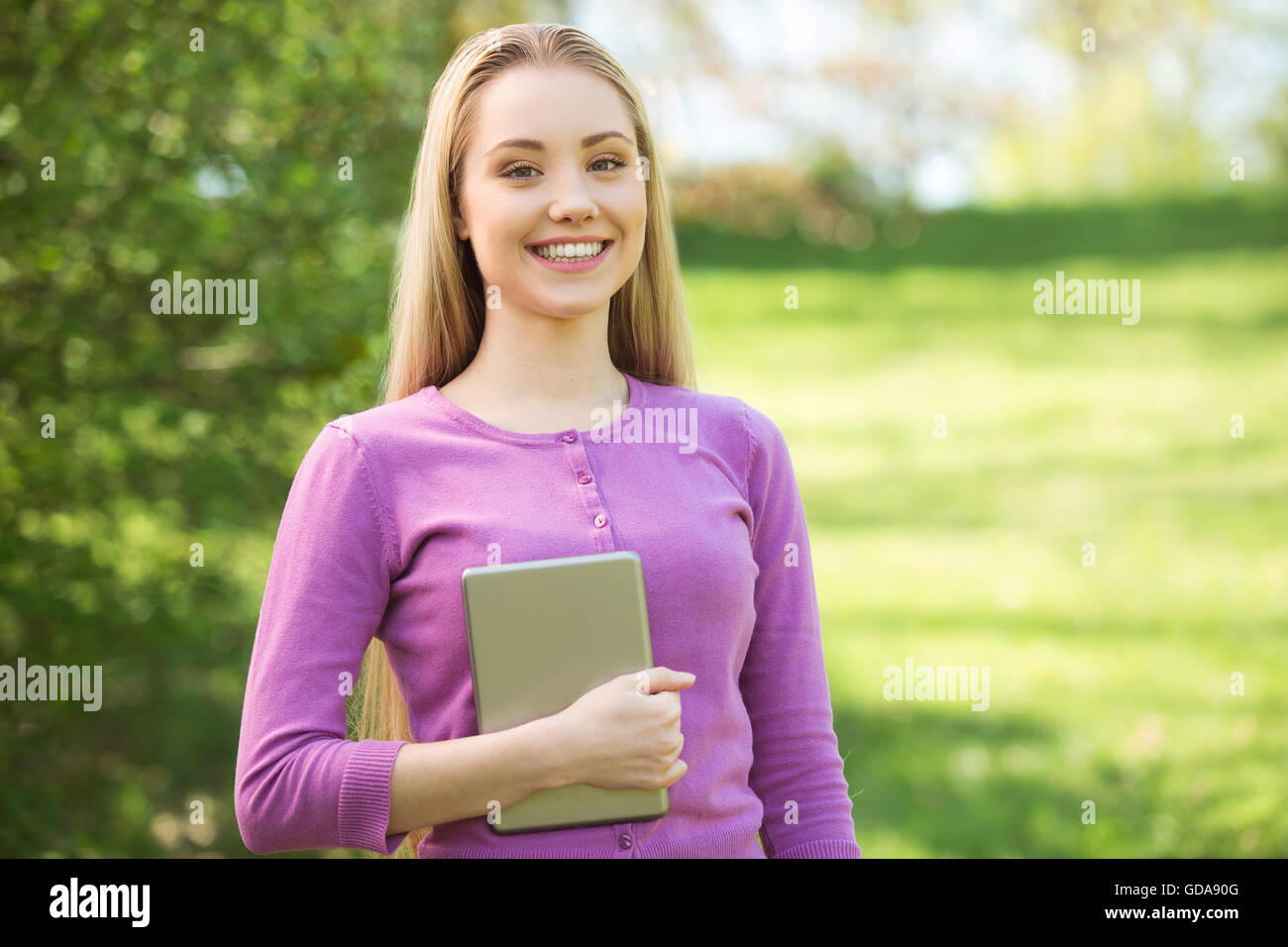 Nice looking young woman outdoors. Woman holding tablet computer and ...