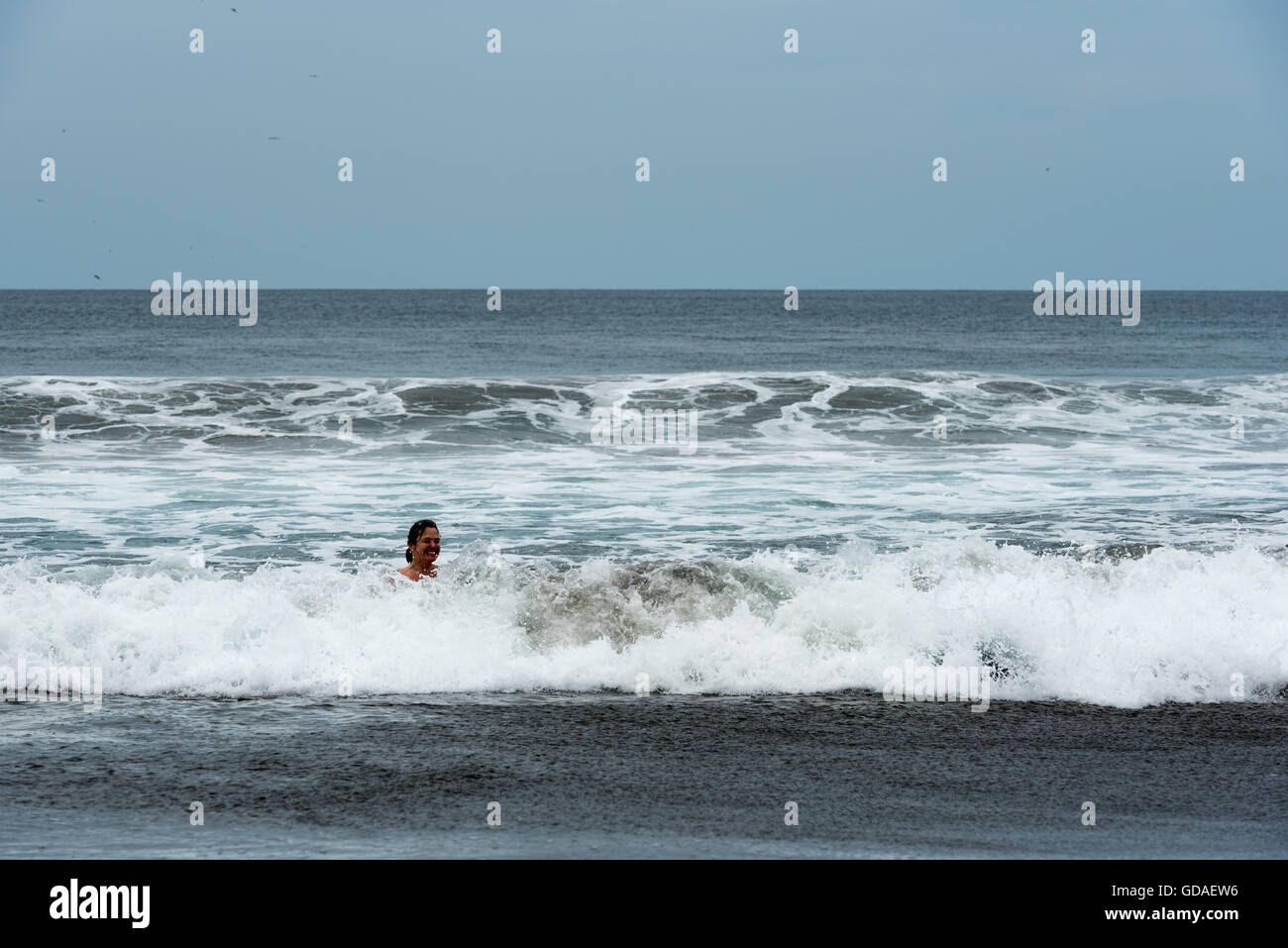 Costa Rica, Guanacaste, Playa Junquillal, Woman floats in the rain in ...