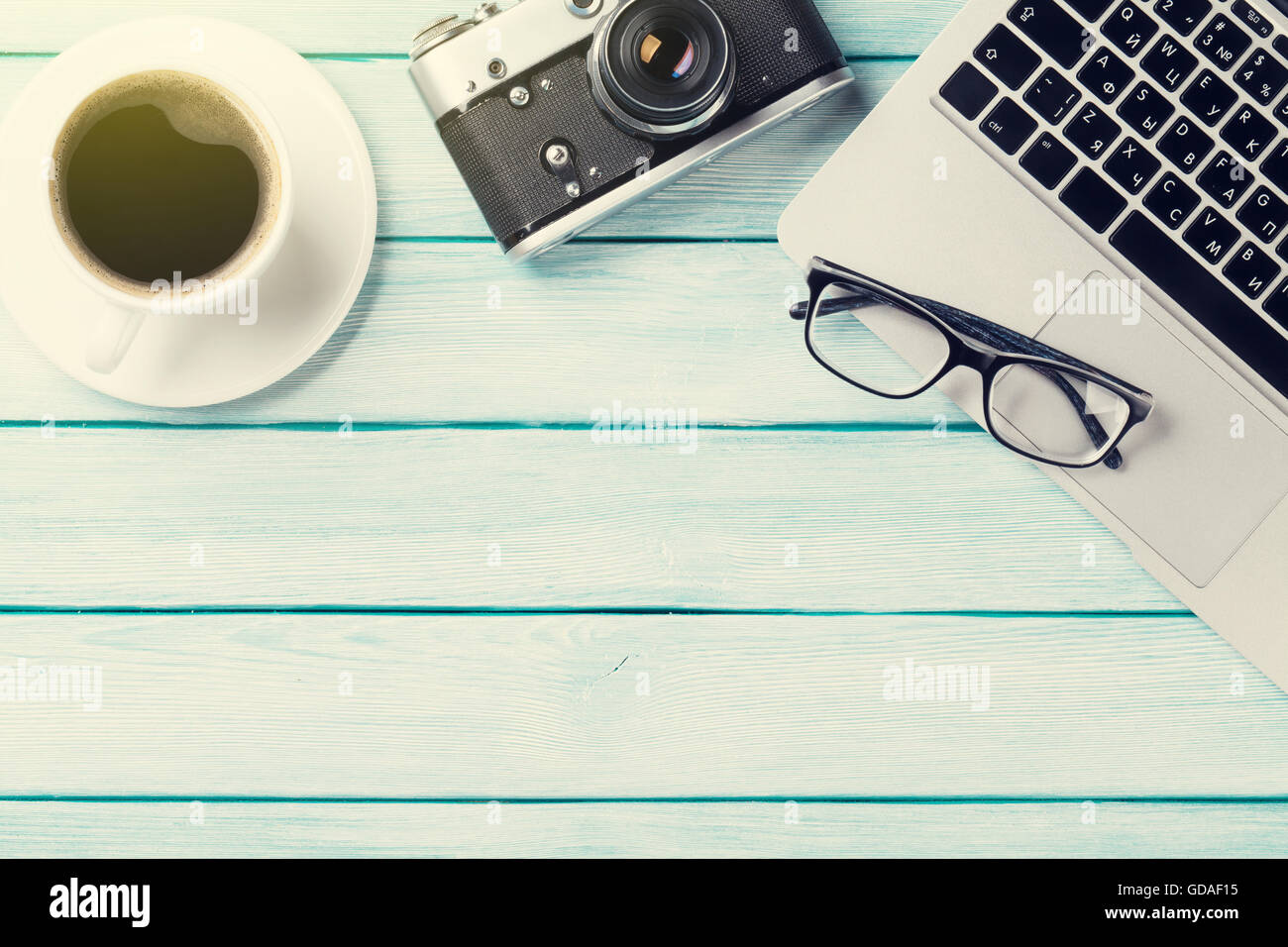Desk table with laptop and camera on wooden table with sun beam ...