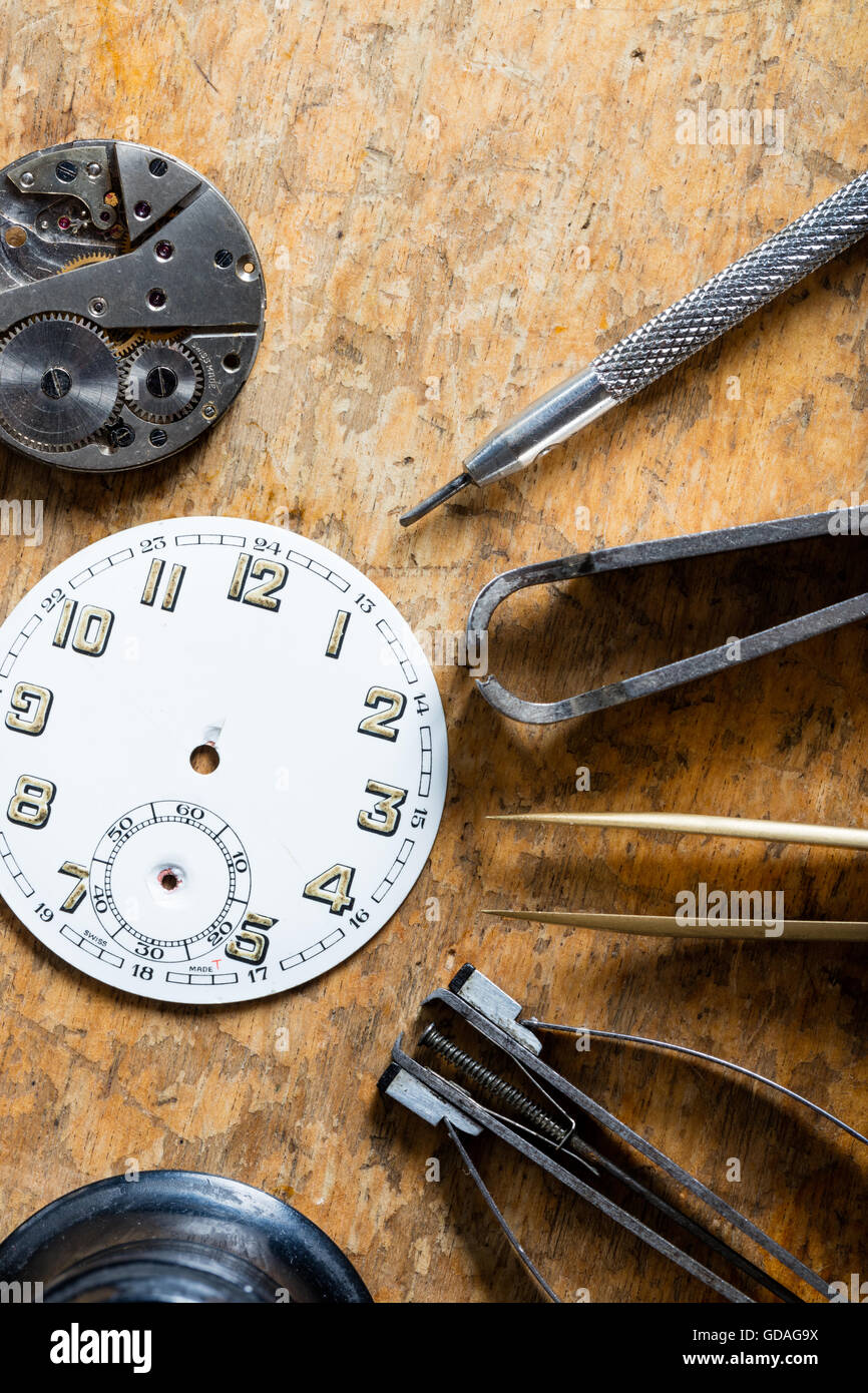 Various horologists tools with a clock dial and mechanism arranged on a ...