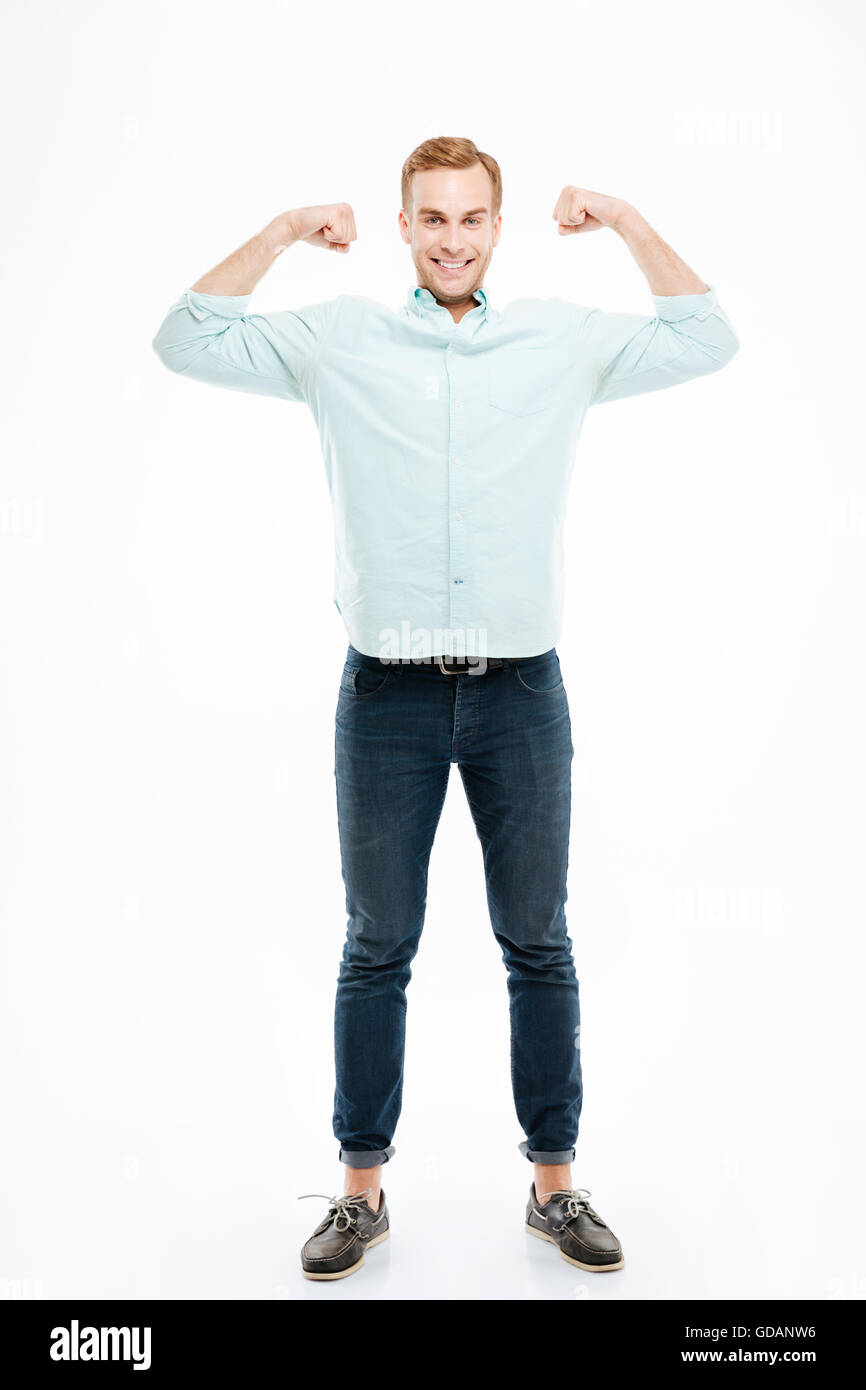 Happy strong young man standing and showing biceps over white ...