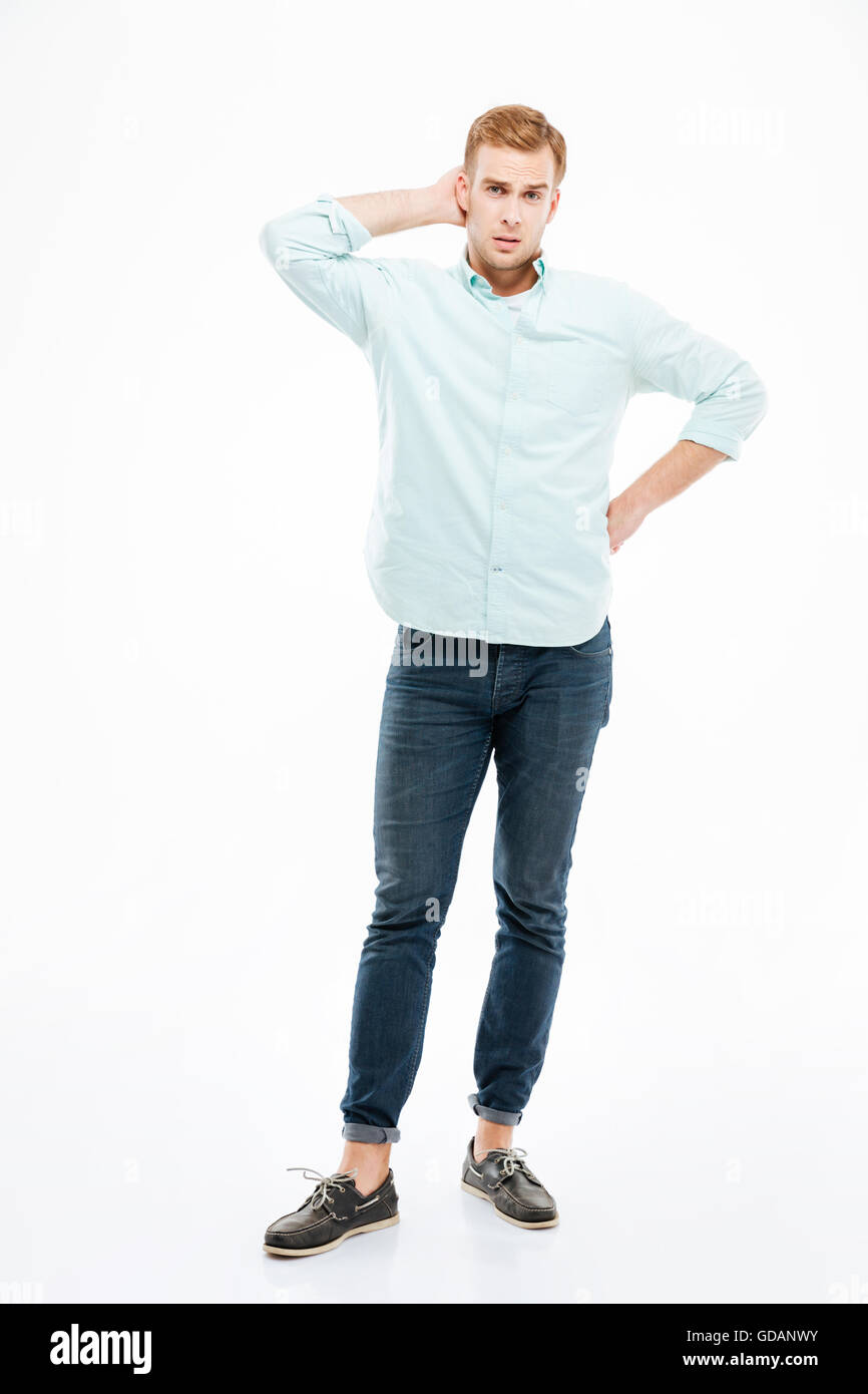 Full length of thoughtful young man standing and thinking over white ...