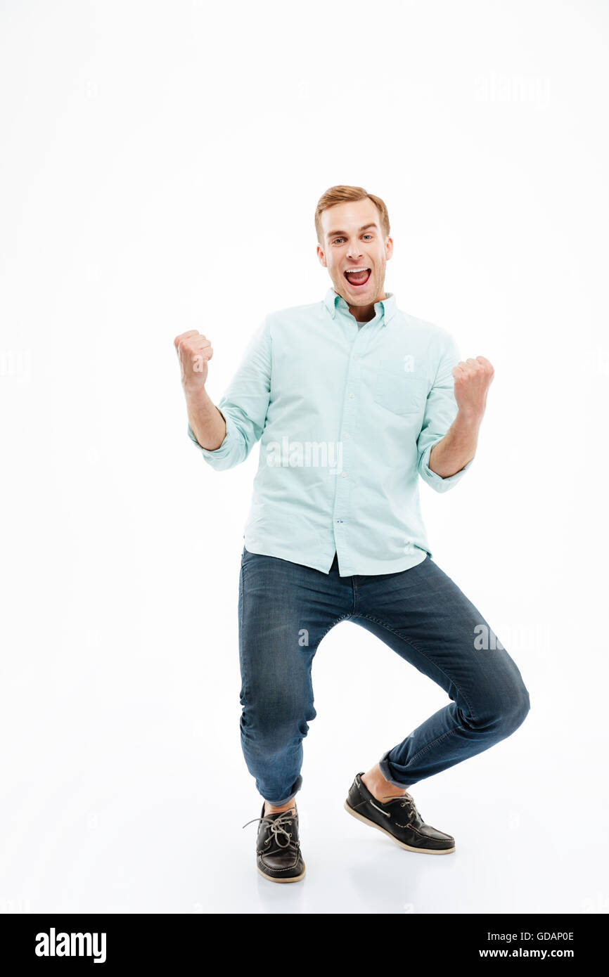 Full length of cheerful young man celebrating success over white ...