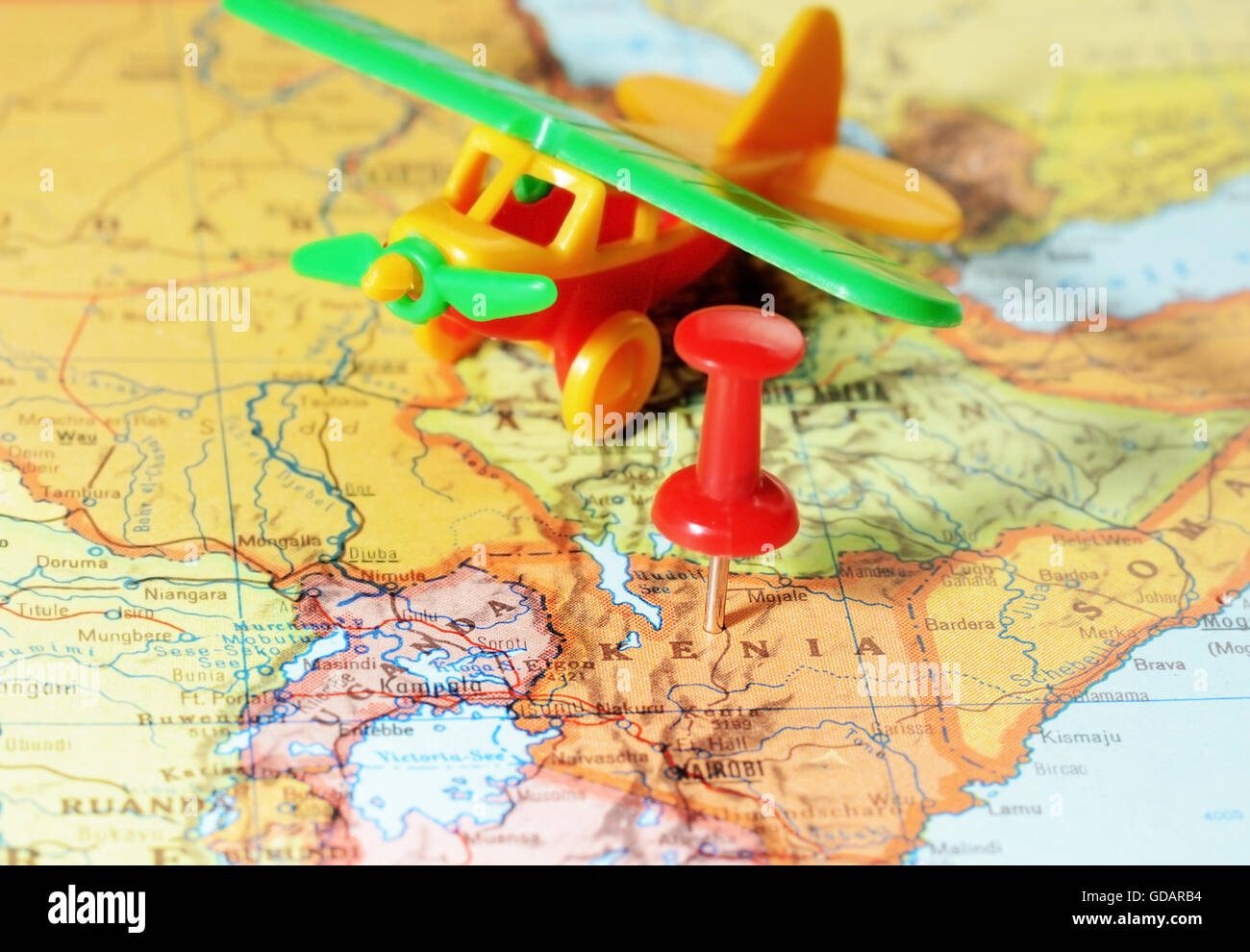 Close-up of a red pushpin on a map of Kenia Africa and airplane toy ...