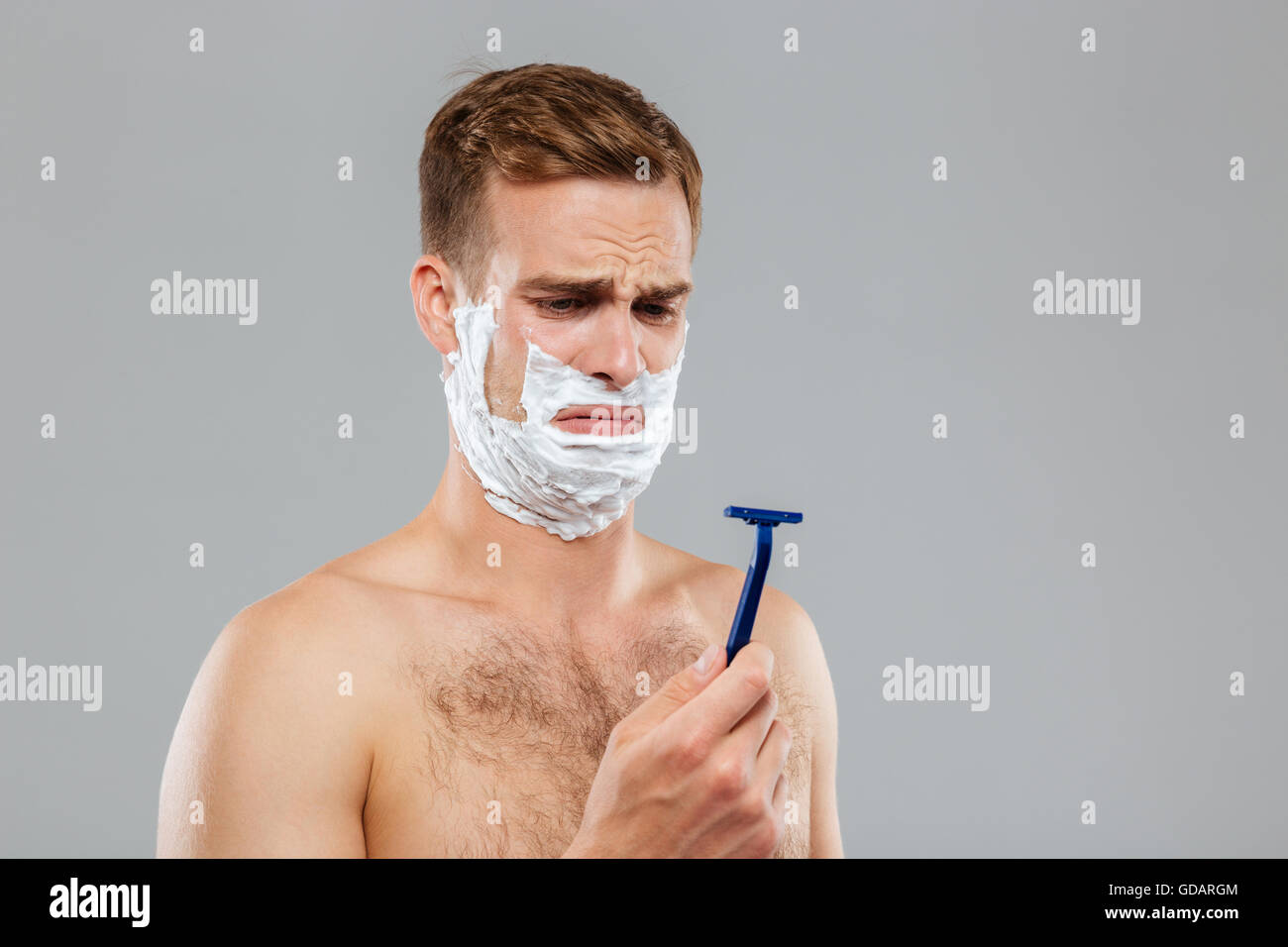 Portrait of a pensive man shaving over gray background Stock Photo - Alamy