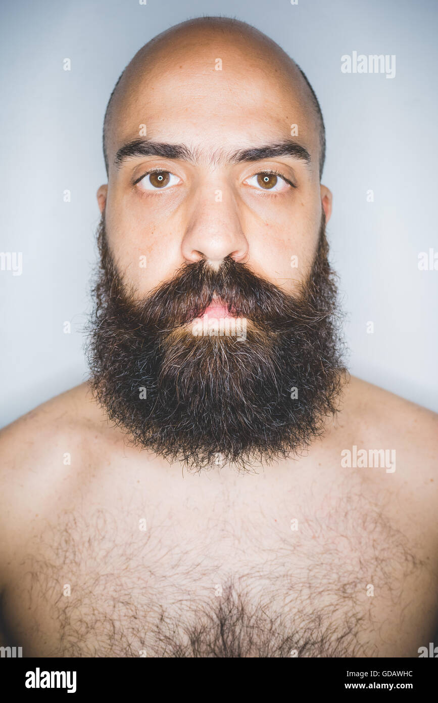 Studio portrait of young mid adult bearded man looking at camera ...