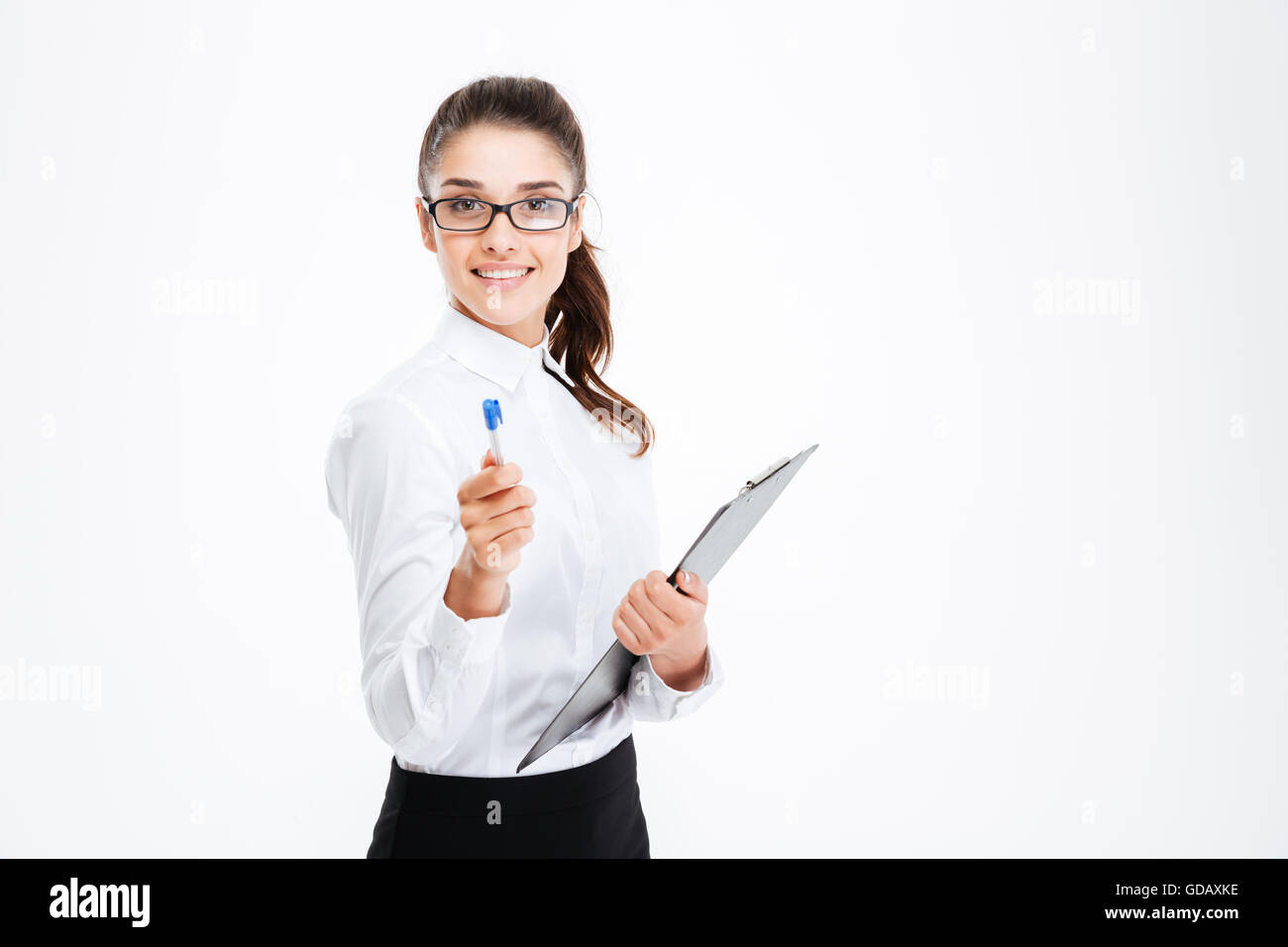 Friendly young smiling businesswoman with clipboard pointing pen at ...