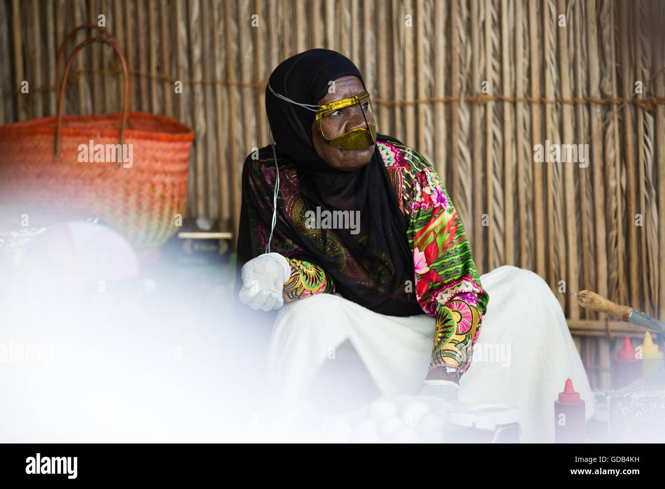 An Emirati lady relaxing whilst waiting for customers at her food stall ...