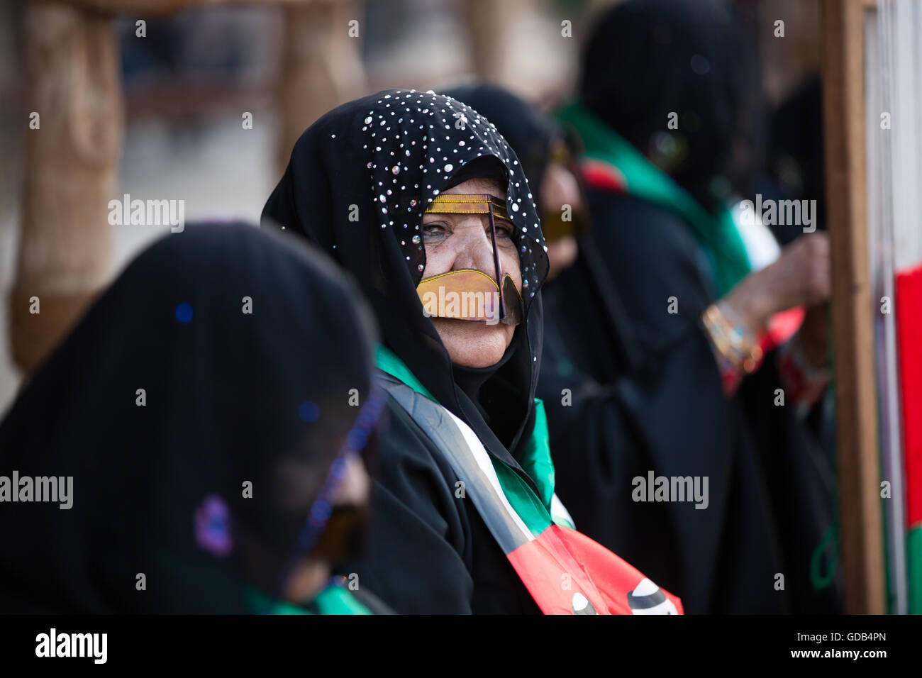 An Emirati woman in an abaya and a gold burqa with the colors of the ...