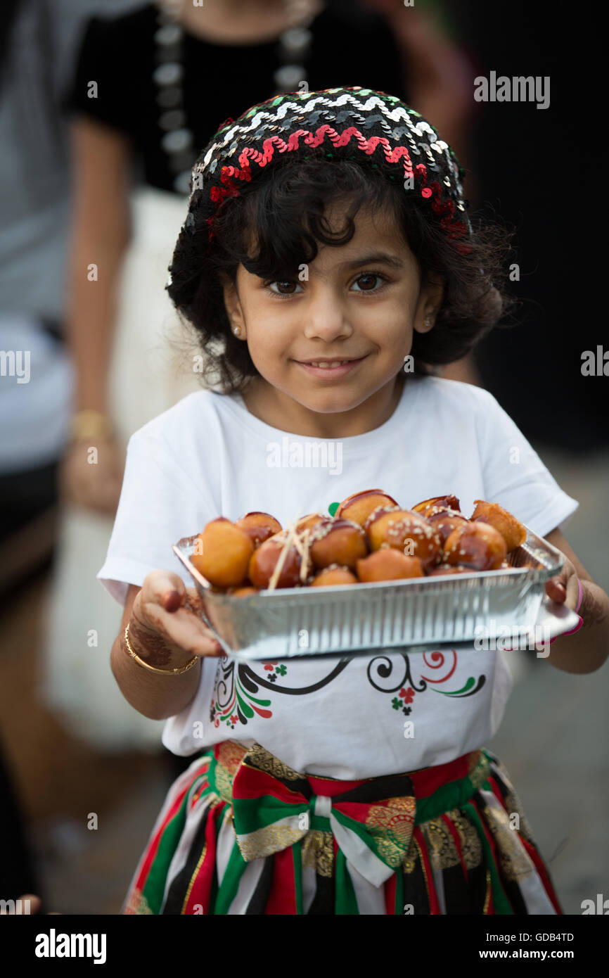 A young Emirati Girl holding a dish of liqamat, a traditional Emirati ...