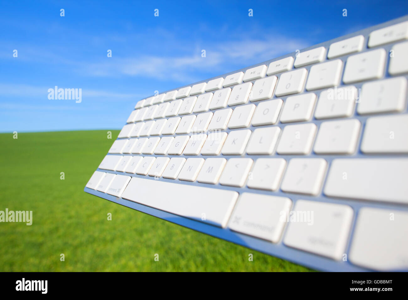 Computer keyboard on sky and grass background Stock Photo - Alamy