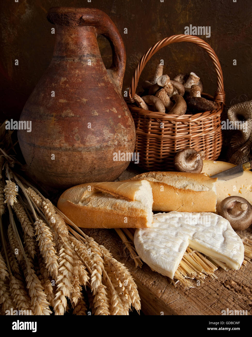 Rustic country still life of bread, cheese and an old wine jar Stock ...