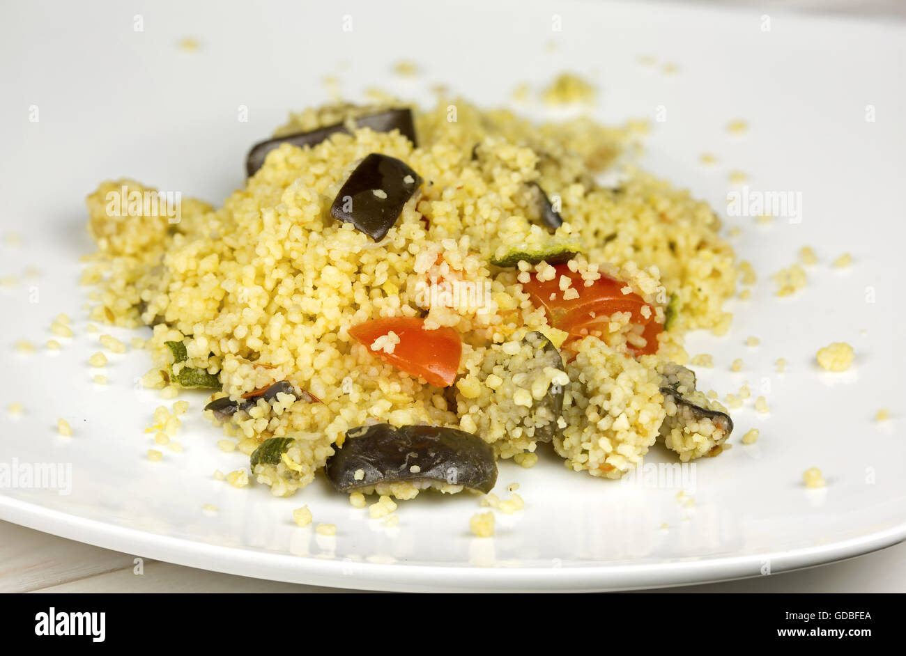 Couscous whit vegetables in a white ceramic plate with wooden ...