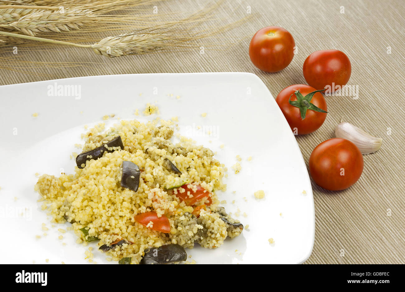 Couscous whit vegetables in a white ceramic plate with wooden ...