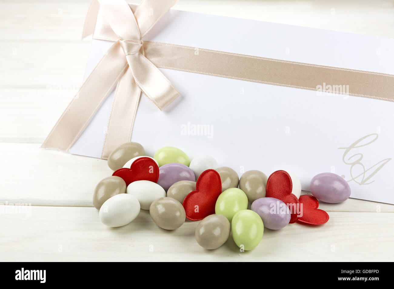 Colored sugared almonds, red heart shaped confetti and wedding paper on ...