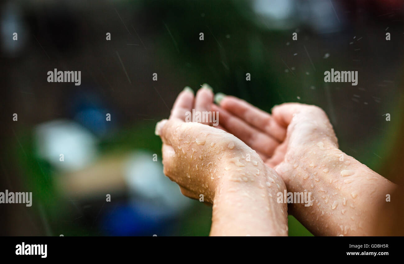 Hands catching clean falling rain water close up. Environmental and ...