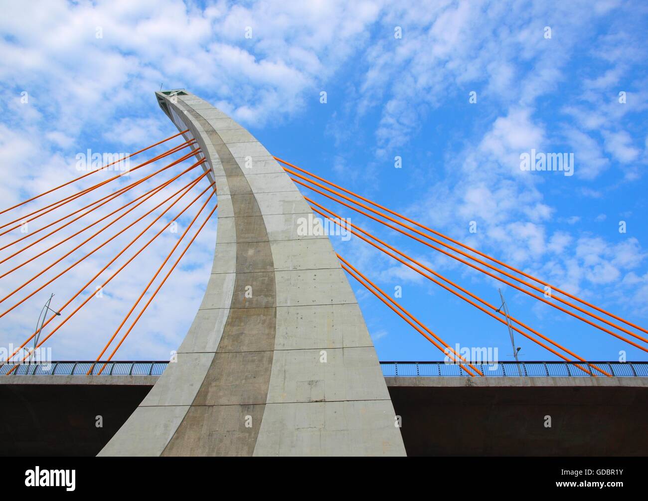 A modern single curved tower of a new bridge with yellow cables Stock ...