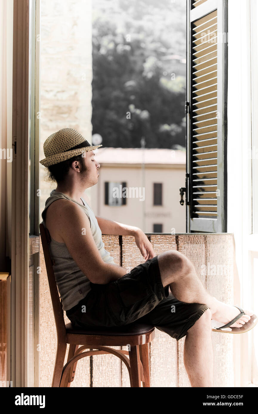 Man with hat sitting next to window Stock Photo - Alamy