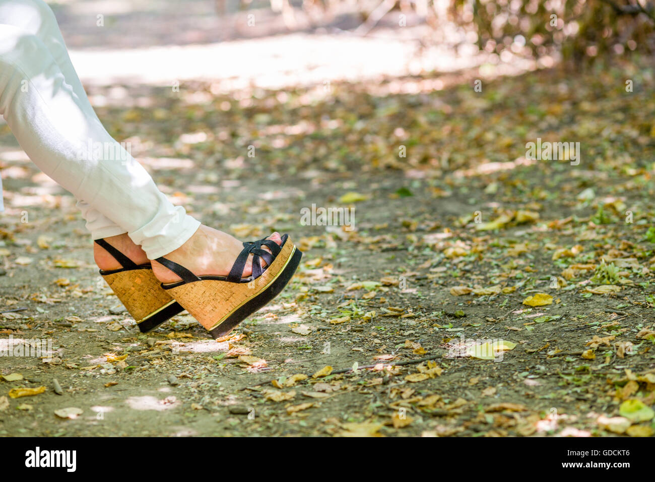 legs of woman sitting on bench in white trousers and high platform ...