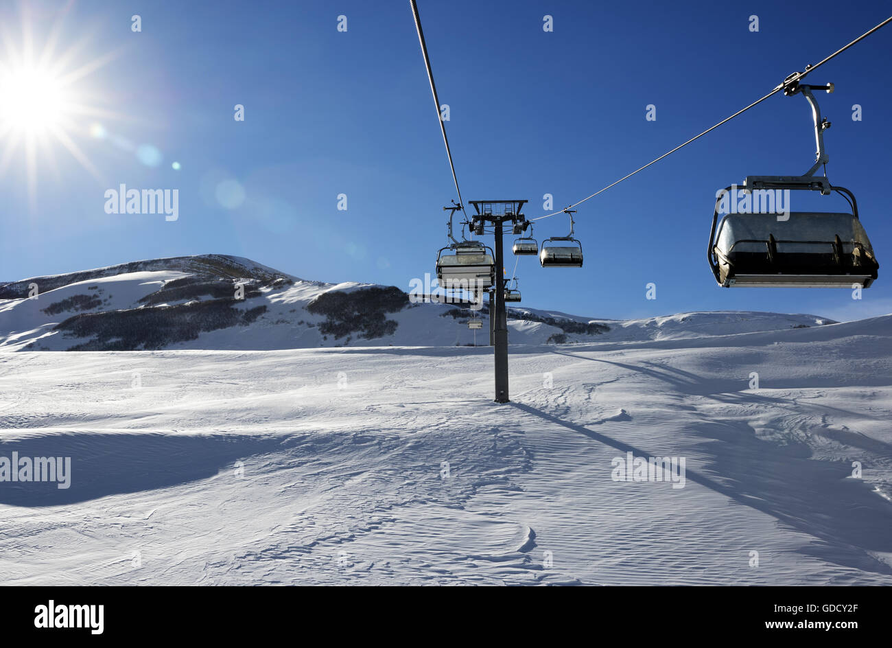 Chair-lift and blue sky with sun. Greater Caucasus, Mount Shahdagh ...