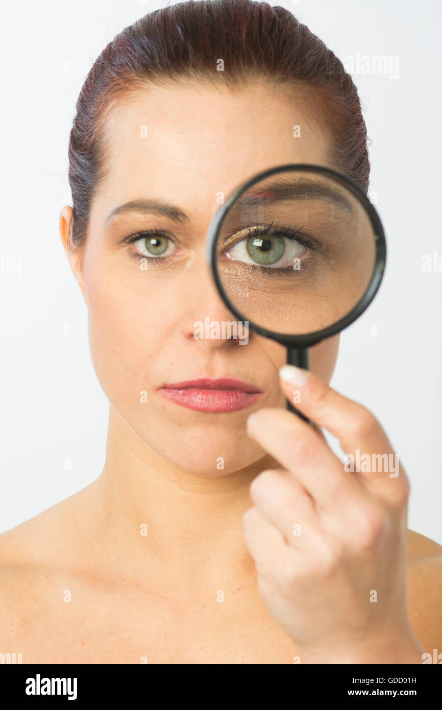 Woman looking through a magnifying glass Stock Photo - Alamy