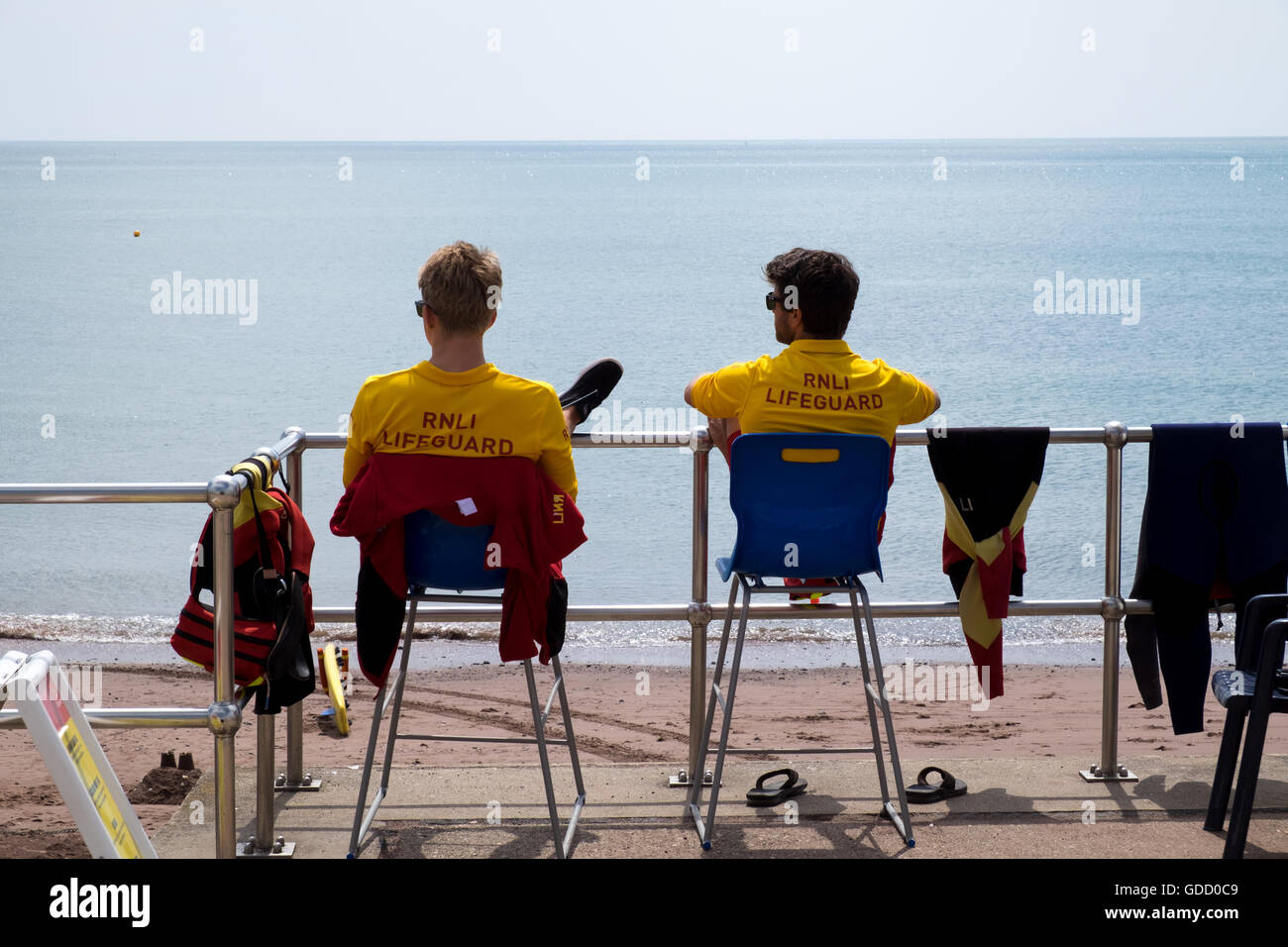 RNLI lifeguards sitting beside the sea at Teignmouth, Devon, England ...