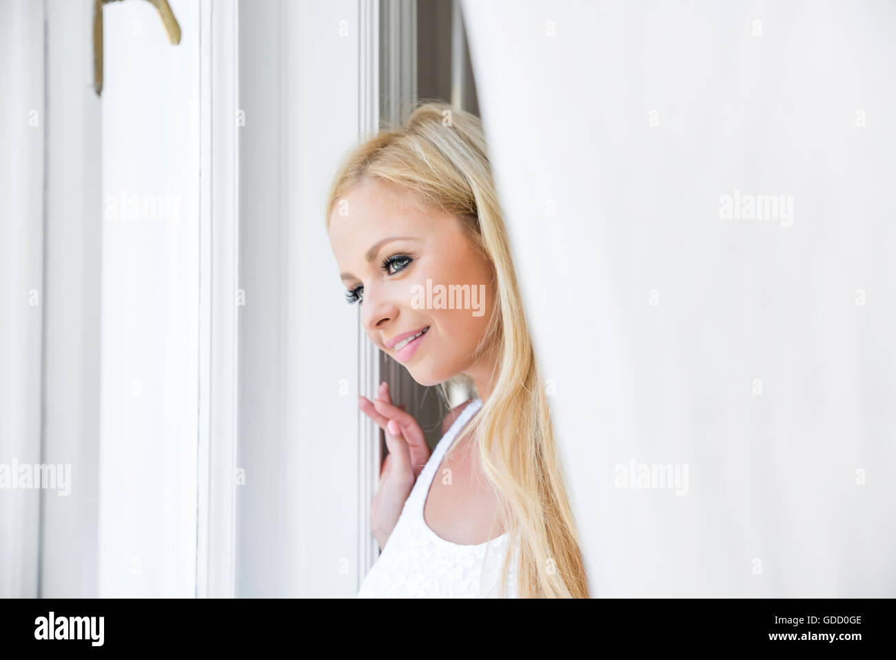 A beautiful young blond woman standing in the window Stock Photo - Alamy