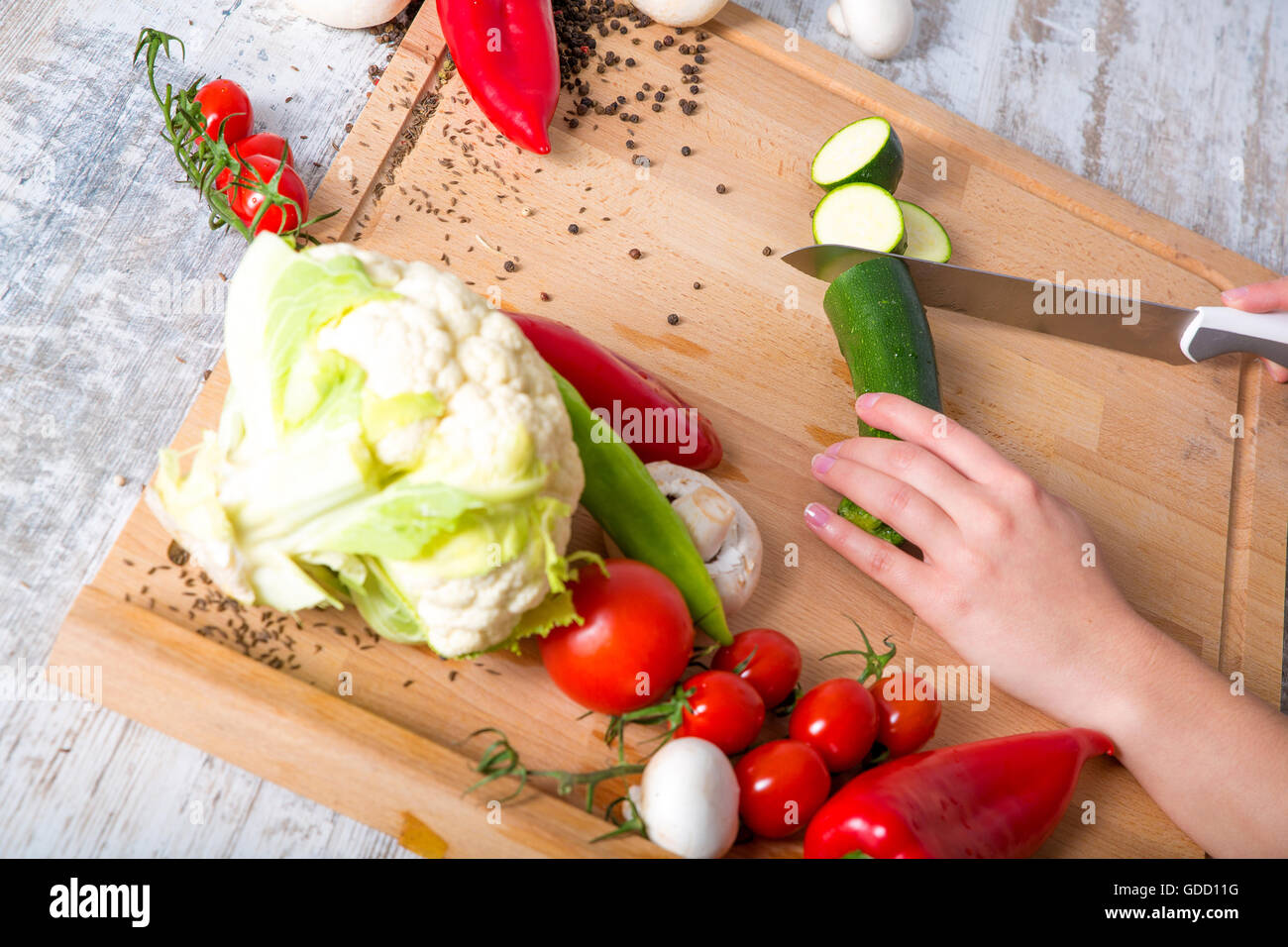 A woman chopping up vegetables at a table Stock Photo - Alamy