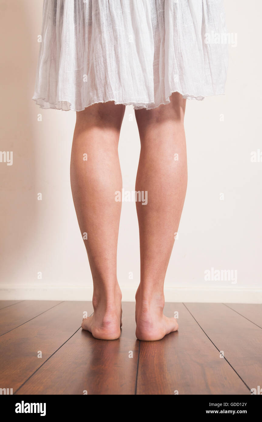 Rear view of a barefooted woman standing on the floor Stock Photo - Alamy