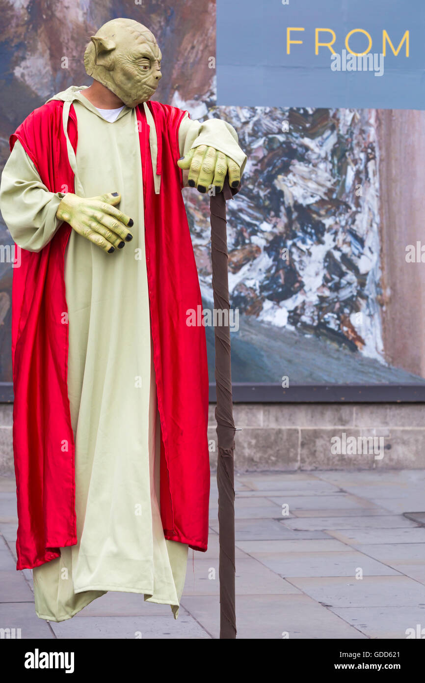 Street artist dressed as Yoda Jedi performing levitating trick outside ...