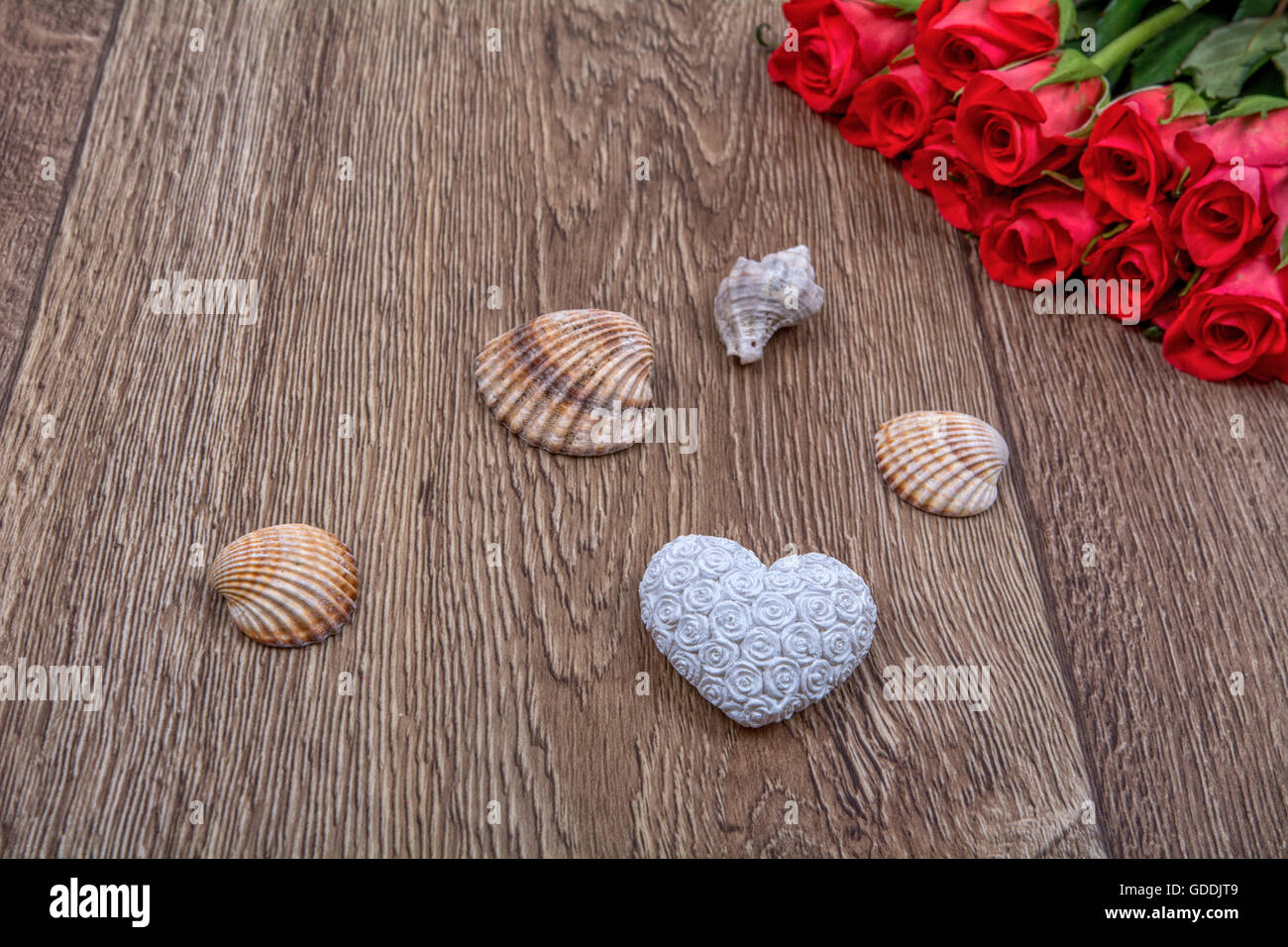 White heart, red roses and shells on a wooden background Stock Photo ...