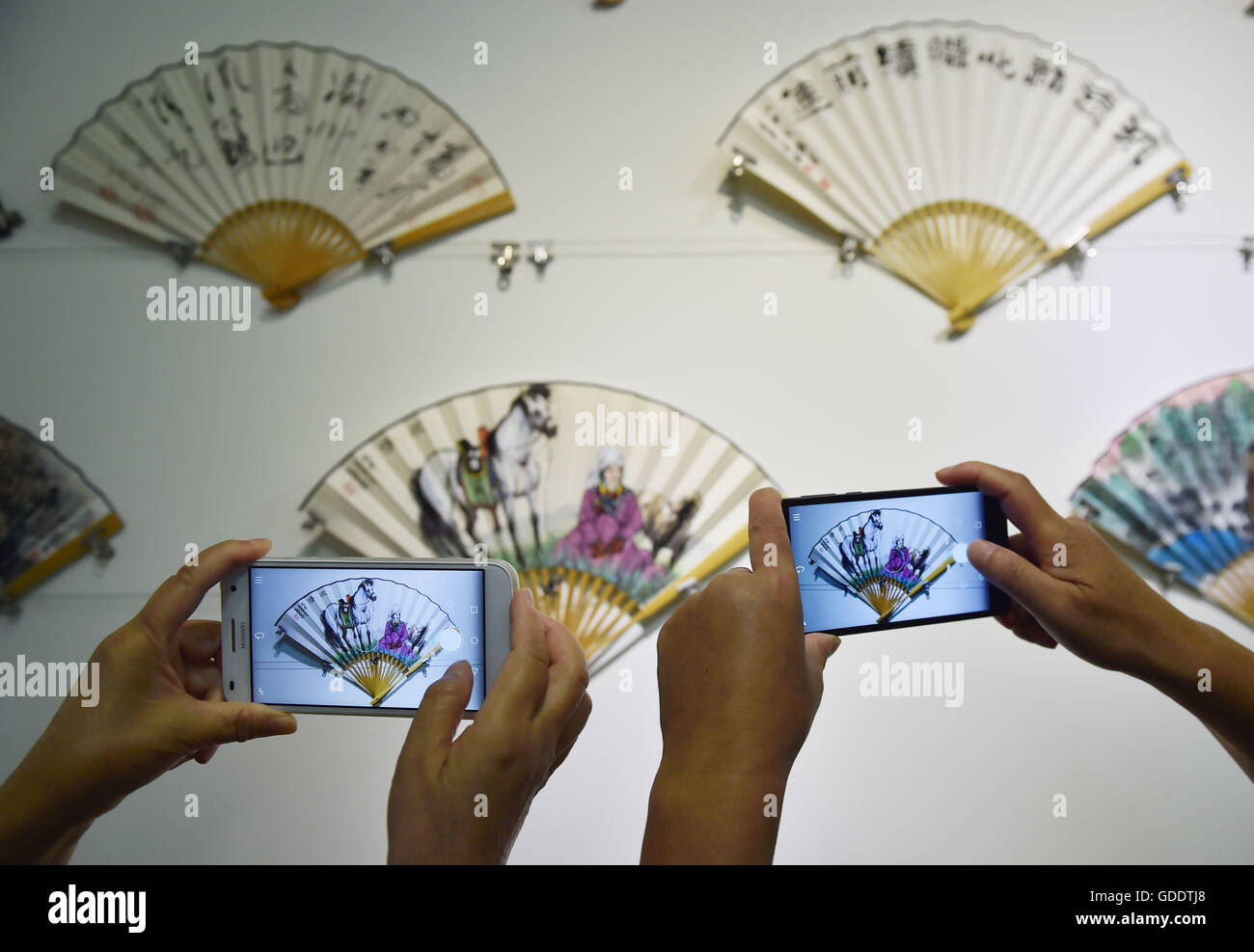 Beijing, China. 15th July, 2016. Visitors take photos of folding fans ...