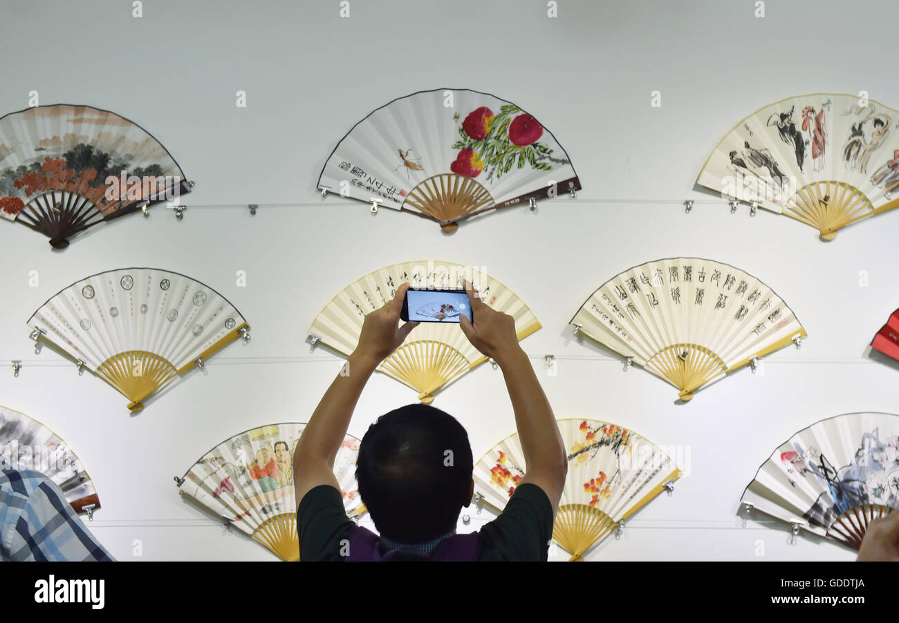 Beijing, China. 15th July, 2016. A visitor takes photos of folding fans ...
