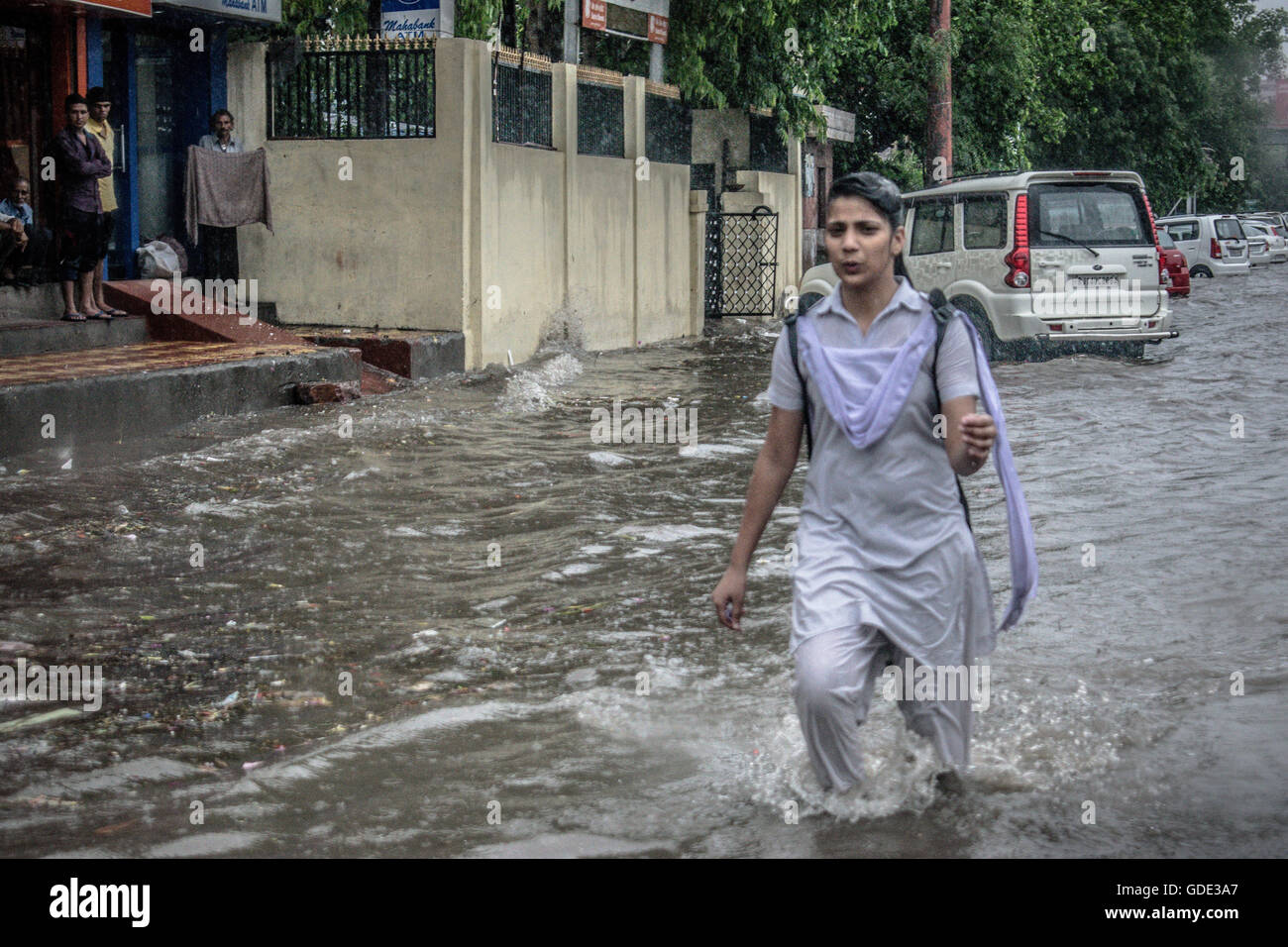 School girl crosses the flooded street as it rains heavily in Jaipur ...